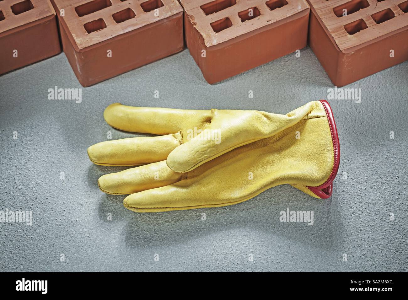 Set of red construction bricks safety gloves on concrete background ...
