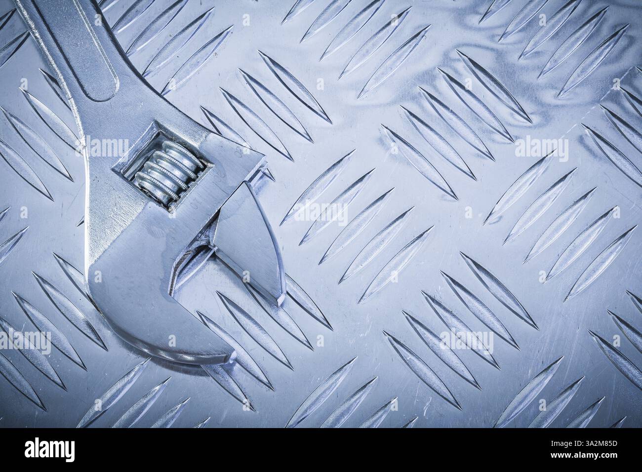 Stainless adjustable wrench on grooved metal plate copy space ...