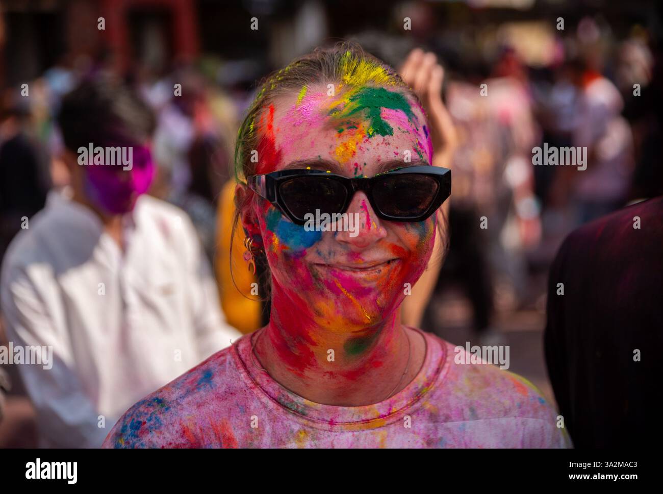 A woman smeared with vermilion powder smiles during the festival. The ...