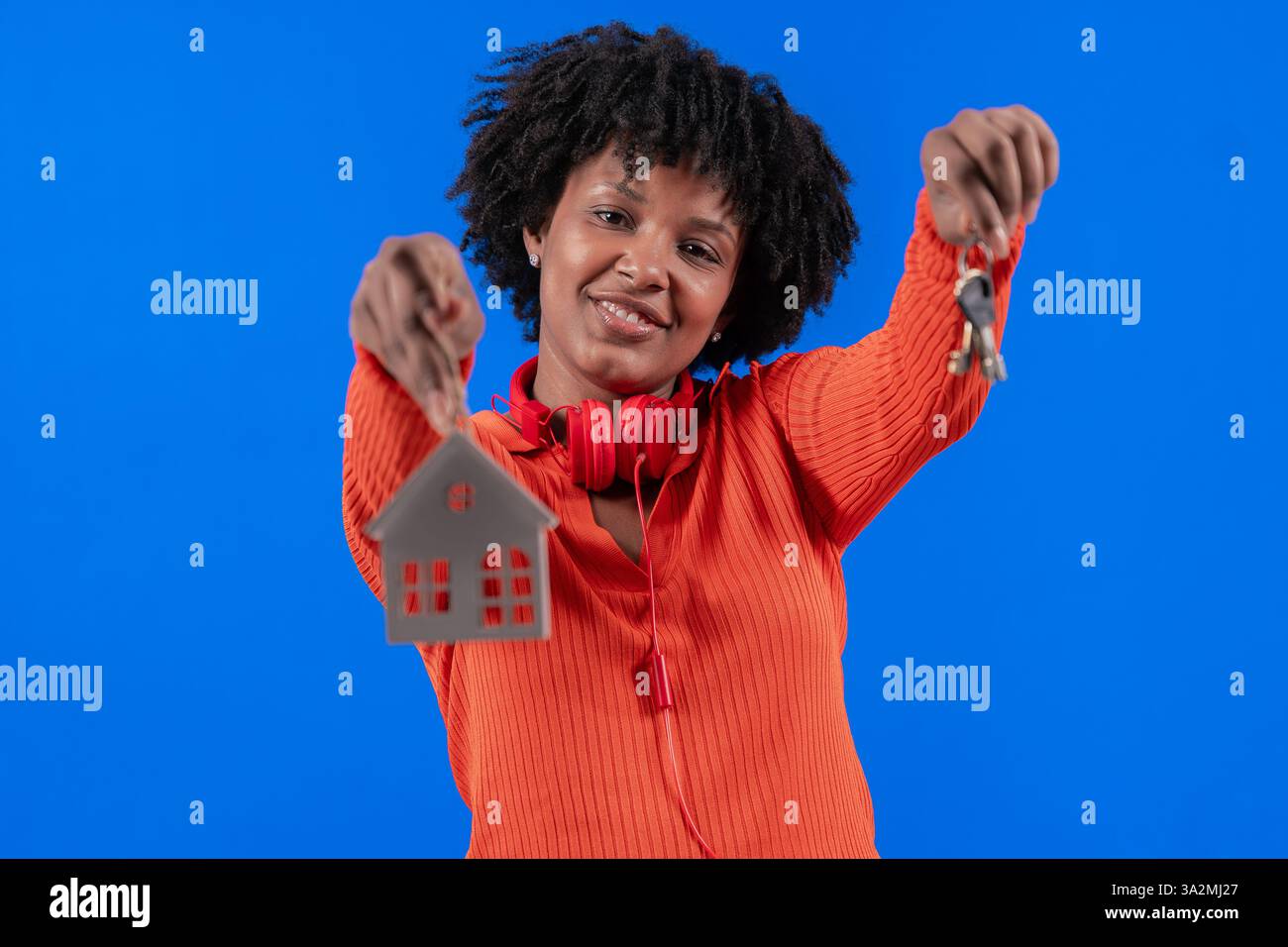 African American woman holding house keys and home model, smiling ...