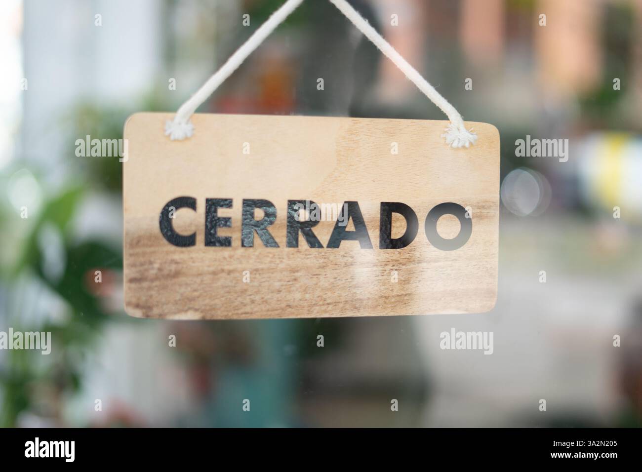 Wooden cerrado sign hanging from a glass door, indicating a flower shop ...