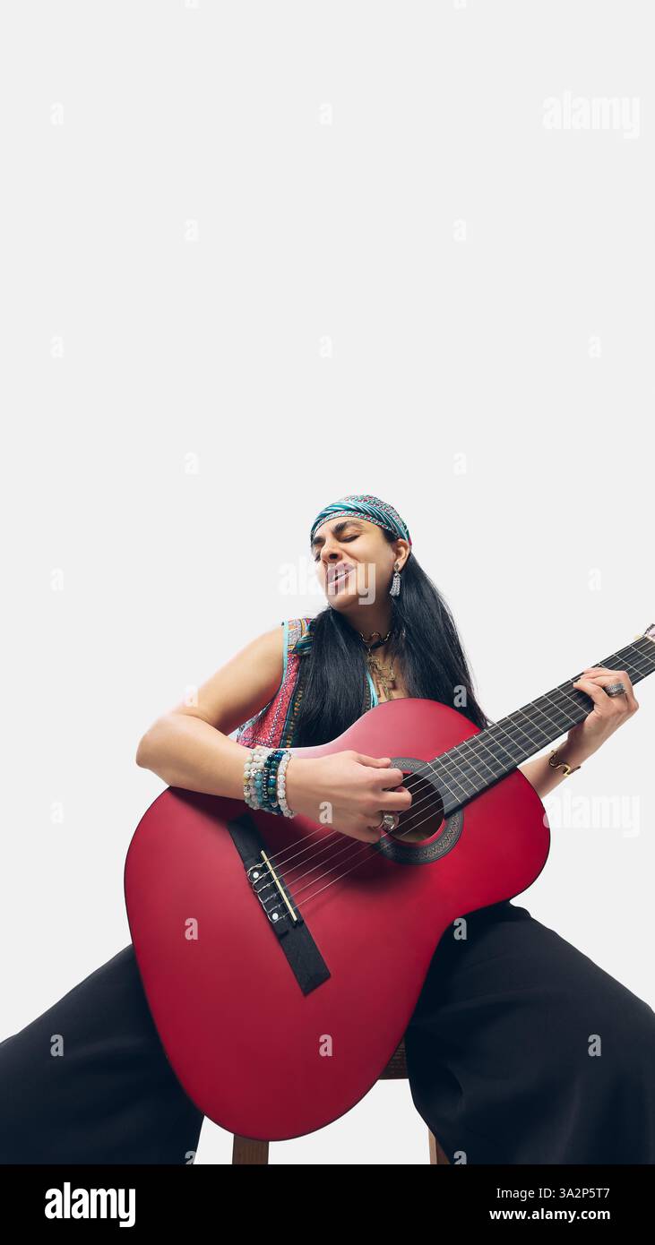 Female guitarist in colorful outfit passionately singing while playing ...