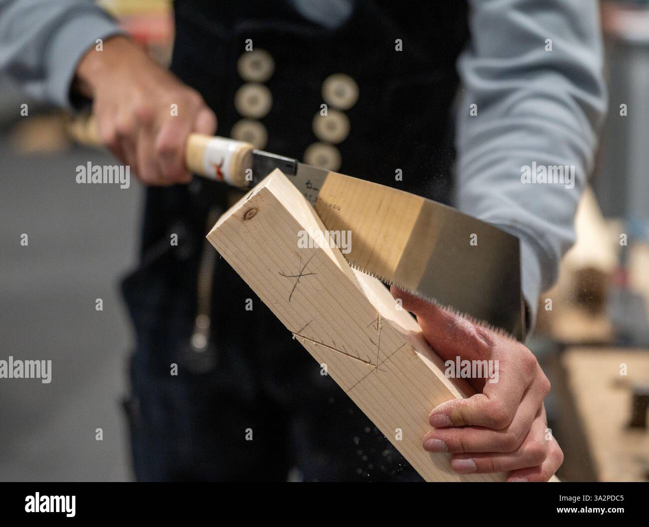 Munich, Germany. 13th Mar, 2025. A carpenter saws a piece of wood at a ...
