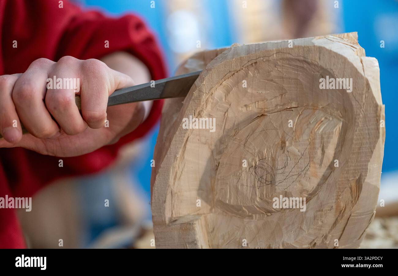 Munich, Germany. 13th Mar, 2025. A wood carver works on a piece of wood ...