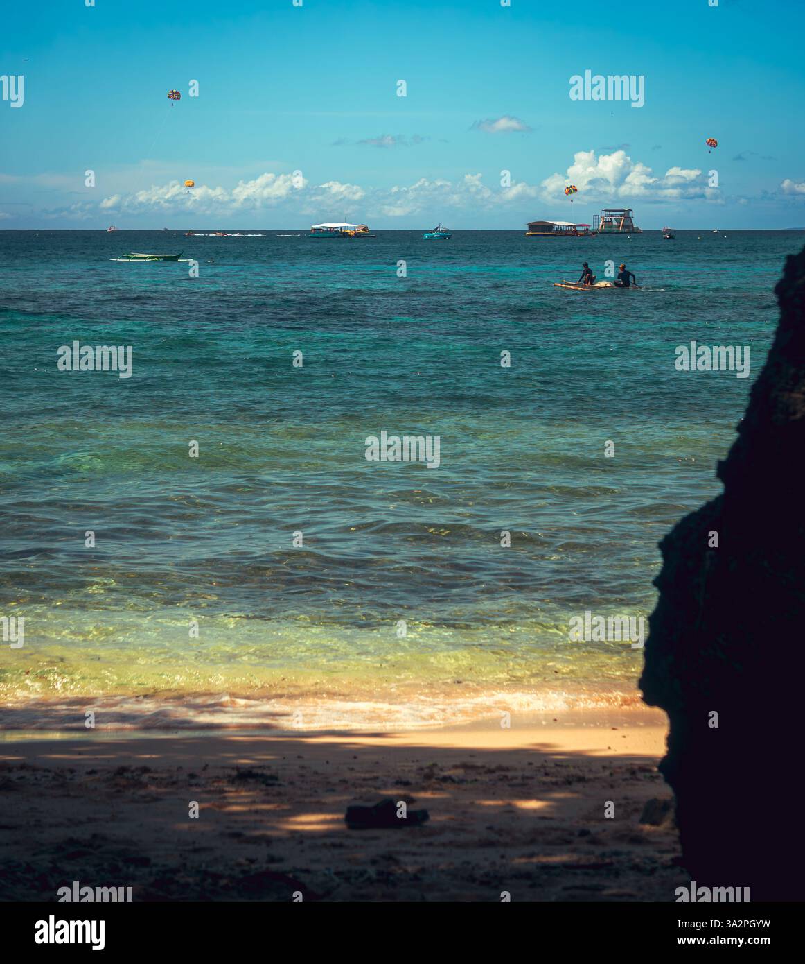 sandy beach in the shade with a view of holiday activities on shallow ...