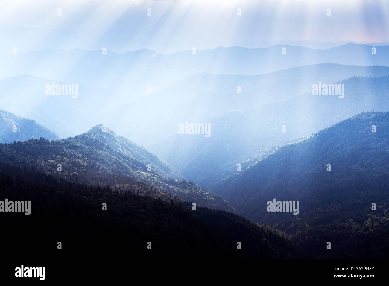 Layers of blue mountains glowing under warm sun rays in a breathtaking ...