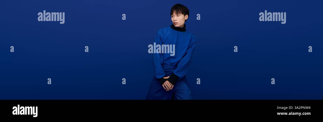 Young man in a blue background showcases his fashion sense thoughtfully ...