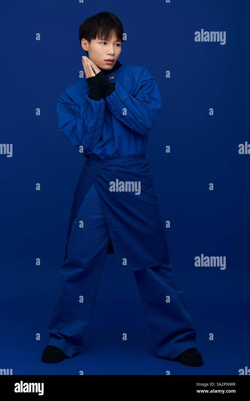 A young handsome asian man stands confidently in a chilling blue outfit ...