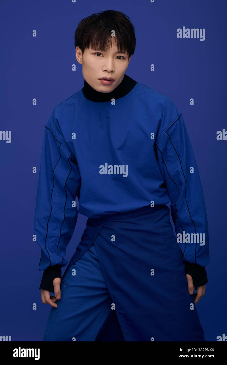 A charming young Asian man stands confidently in a striking blue outfit ...