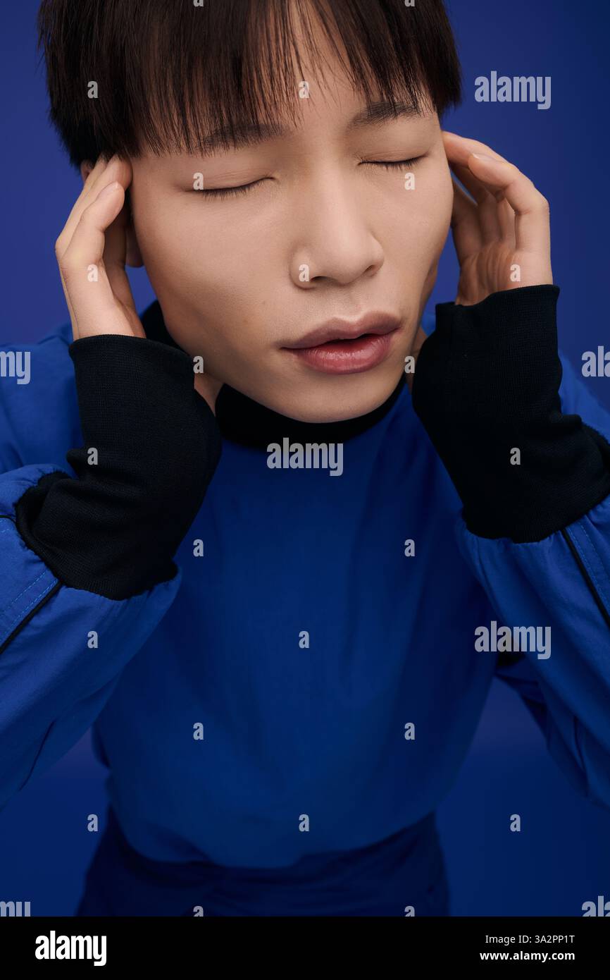 A handsome young Asian man with closed eyes displays deep emotion in a ...