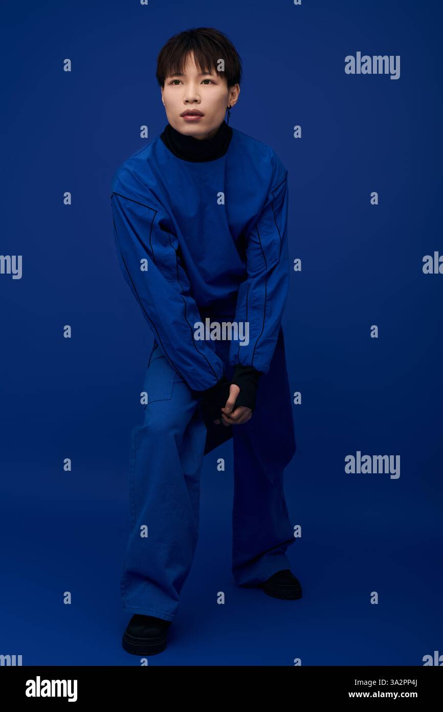 A young Asian man in a bold blue outfit poses confidently against a ...