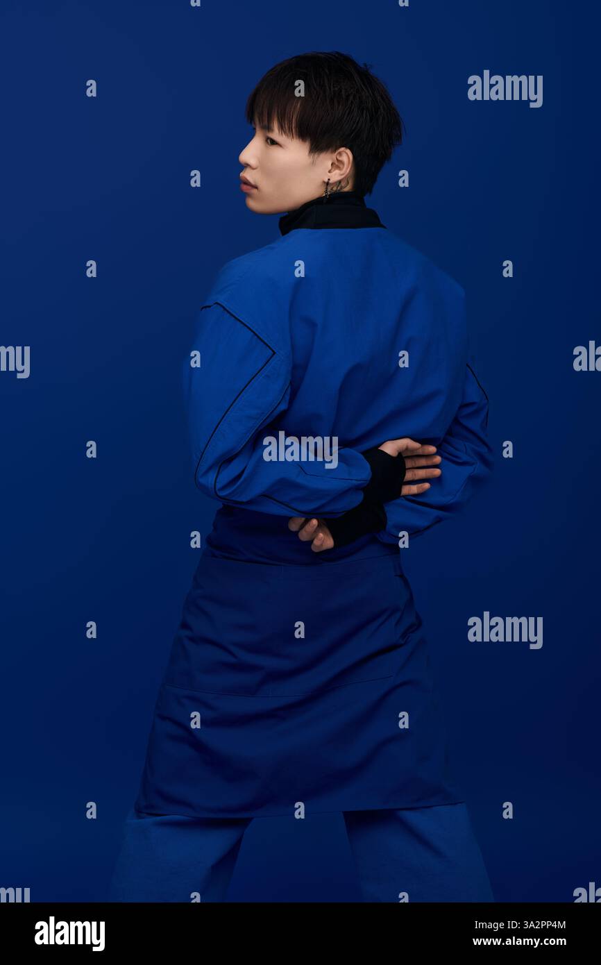Attractive young asian man showcases a vibrant blue garment while ...