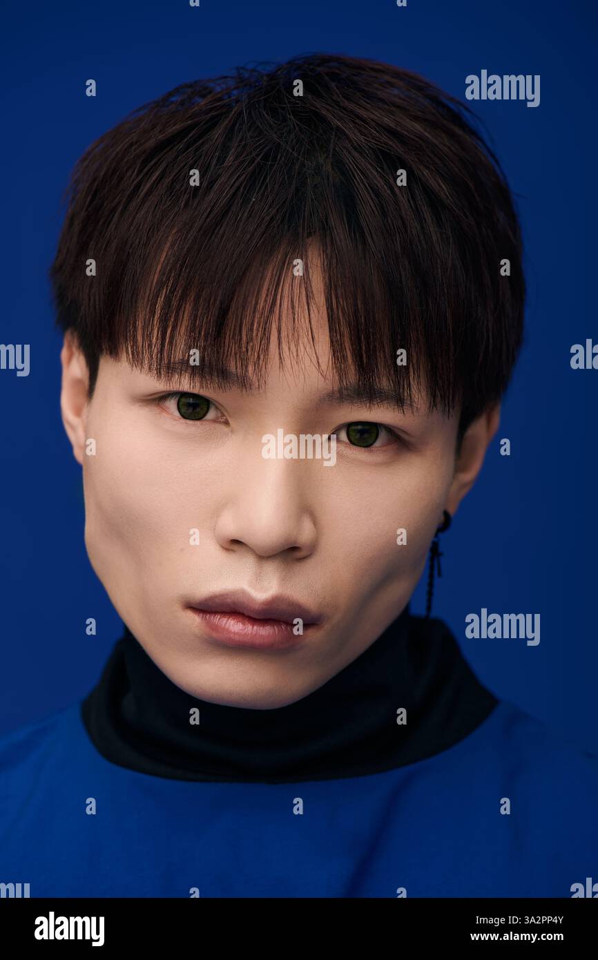 A striking young Asian man gazes intently, showcasing his attractive ...