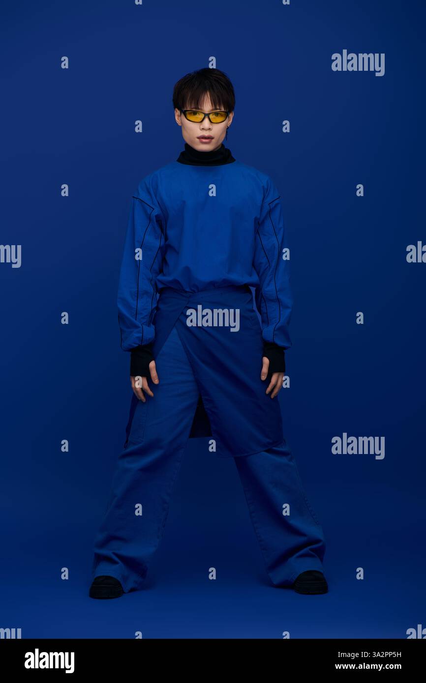 A young attractive asian man stands confidently in a bold blue outfit ...