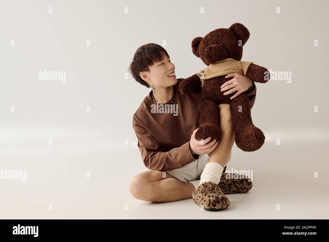 Cheerful young man engages in playful interaction with a cute teddy ...