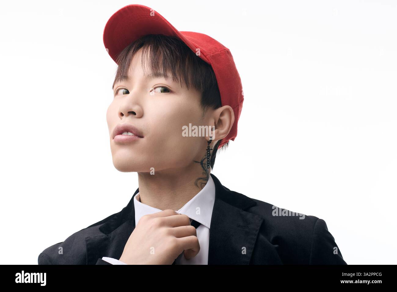 A stylish young Asian man adjusts his suit and cap with confident charm ...