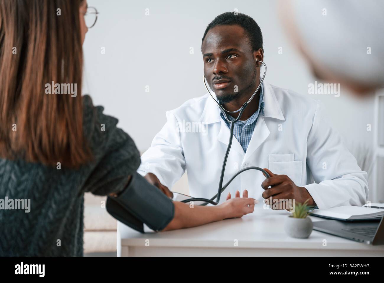 Customer service. A doctor measures a young woman's blood pressure ...