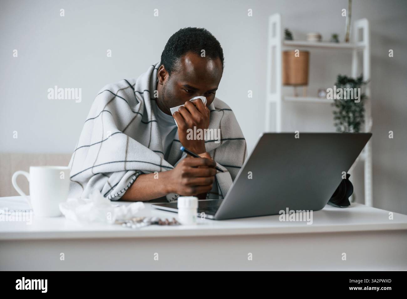 Working from home by laptop. Feeling bad. Sick black man is at home ...