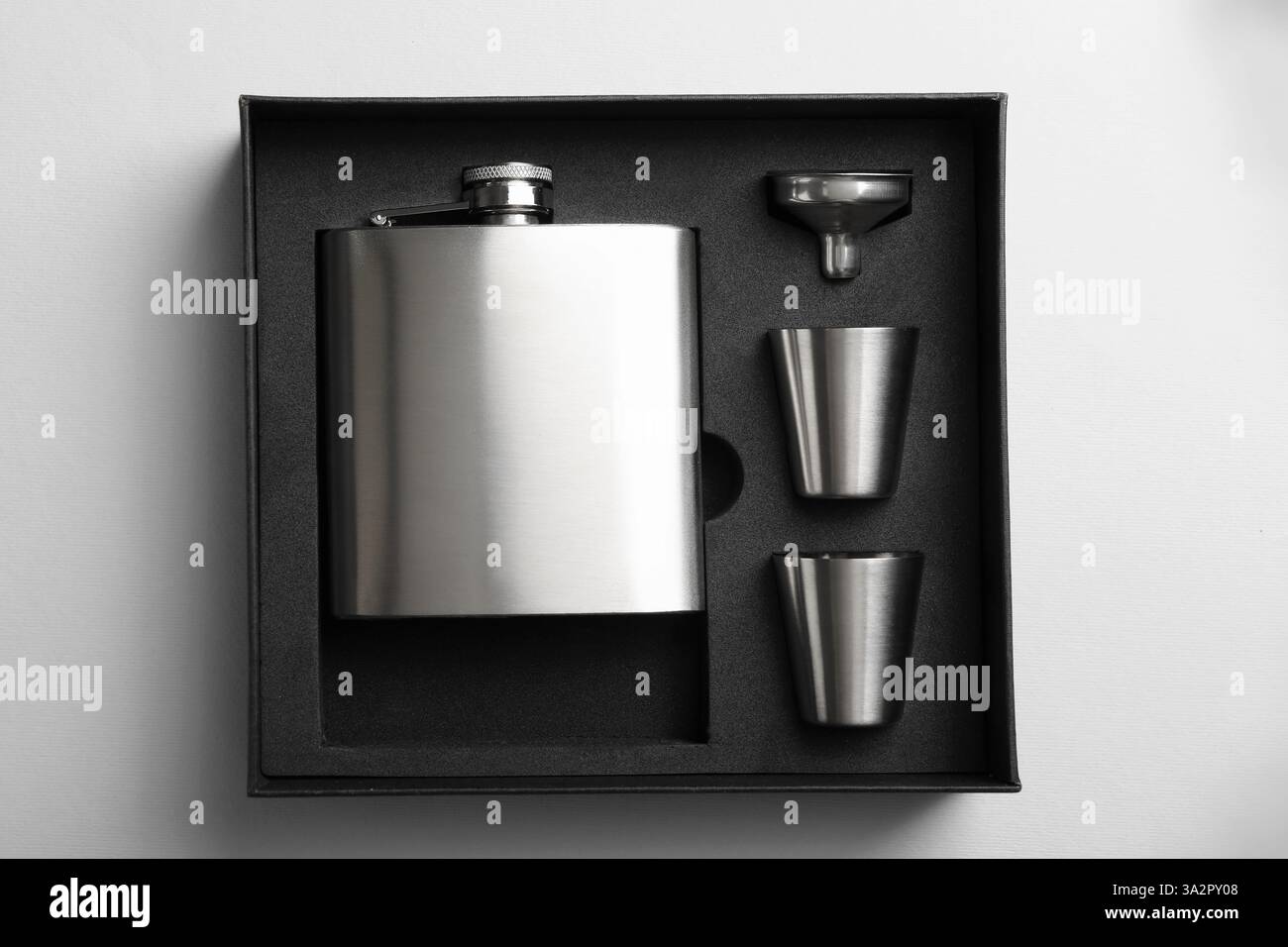Hip flask, cups and funnel in package on white background, top view ...