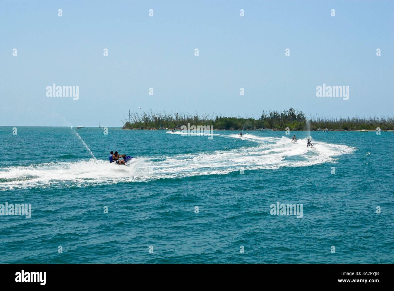 Parade of jet skis curve around key in waters off key west Florida ...