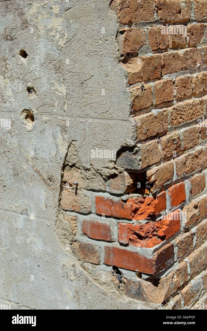 Close up deteriorating corner of brick building with partial stucco ...