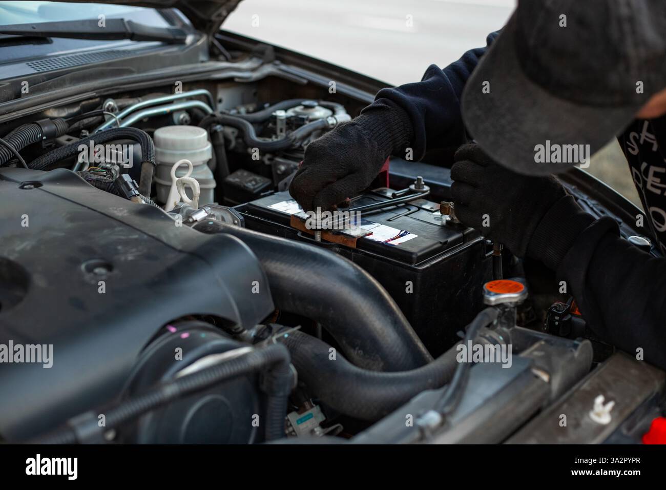 Replacing a car battery. A man installs a battery by installing a ...