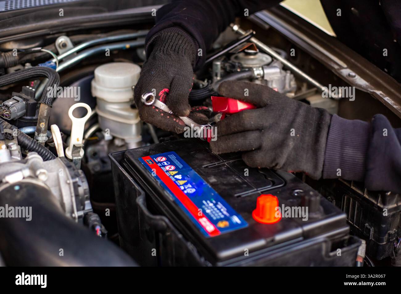 Replacing a car battery. A man installs a battery by tightening the ...