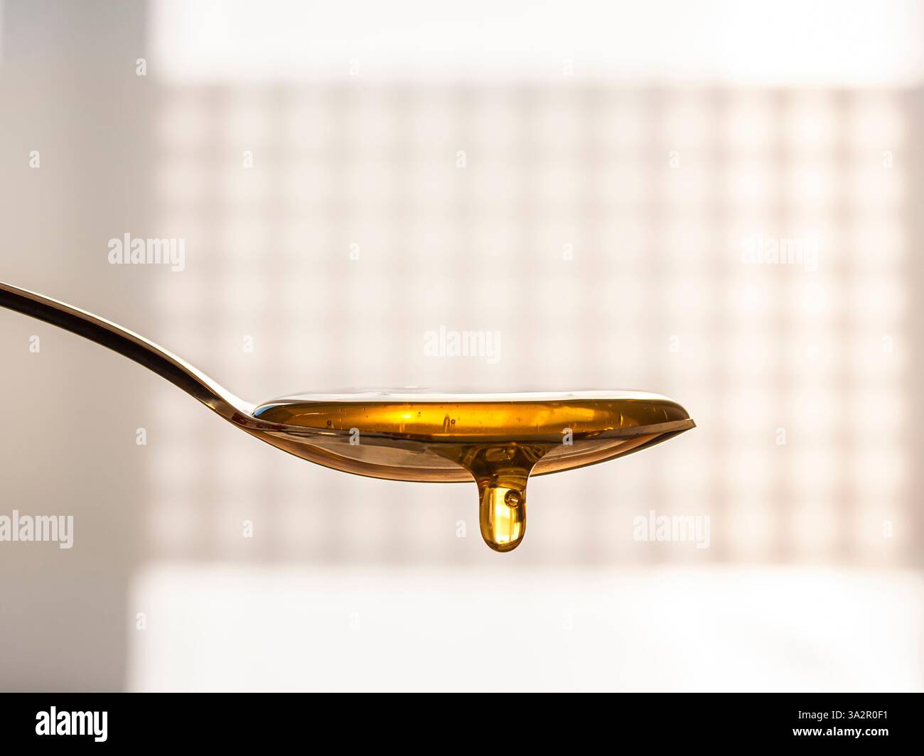 close-up of a spoon with golden honey dripping, against a softly lit ...
