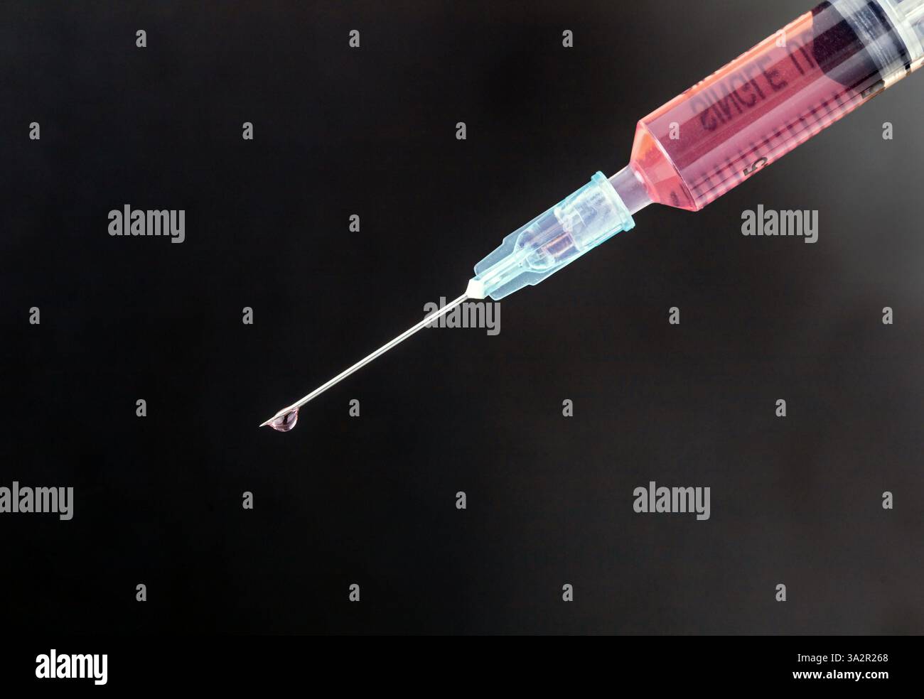 Syringe with red liquid on a black background representing medical ...