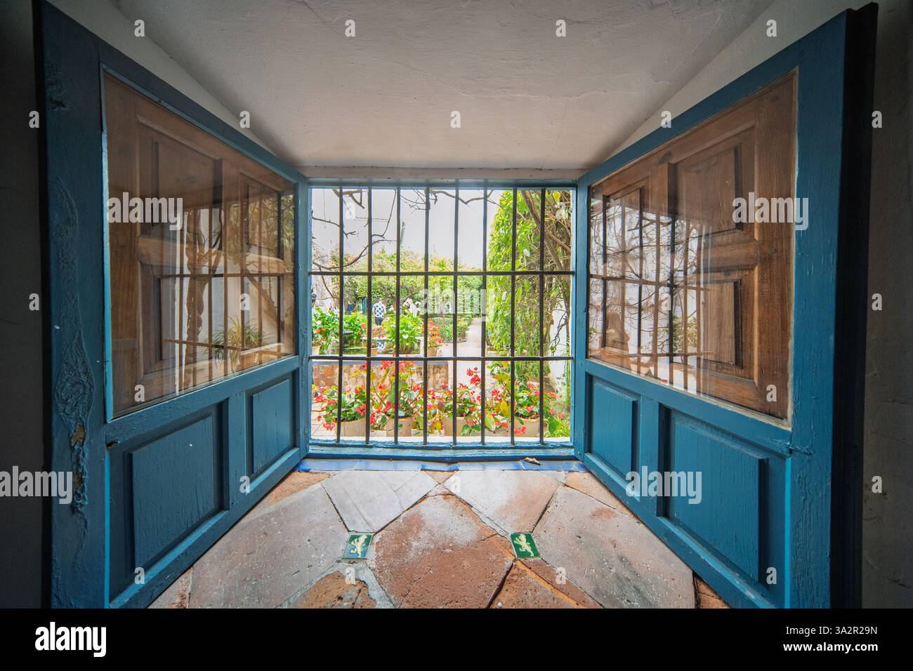 Open blue windows offer a glimpse into a vibrant courtyard full of ...