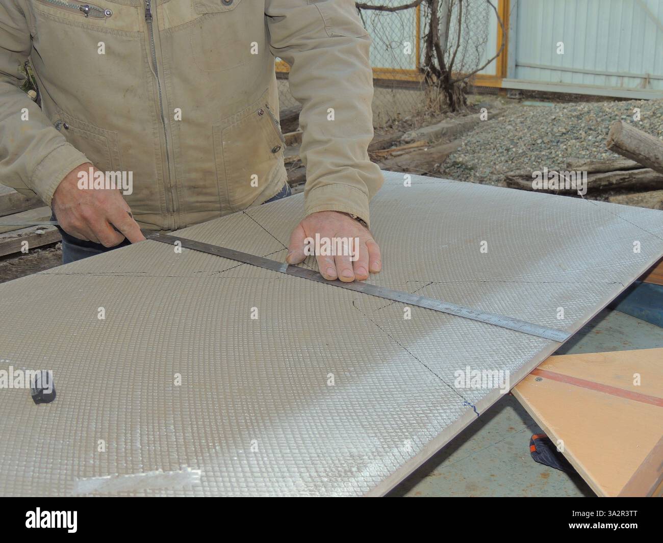 man measuring distance on back of large finishing tile on outdoor ...