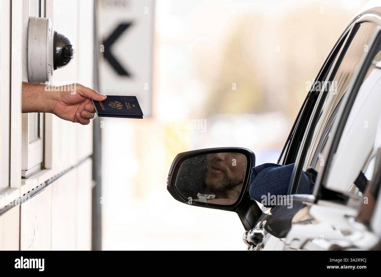 A Canada Border Services officer hands passports back to a visitor ...