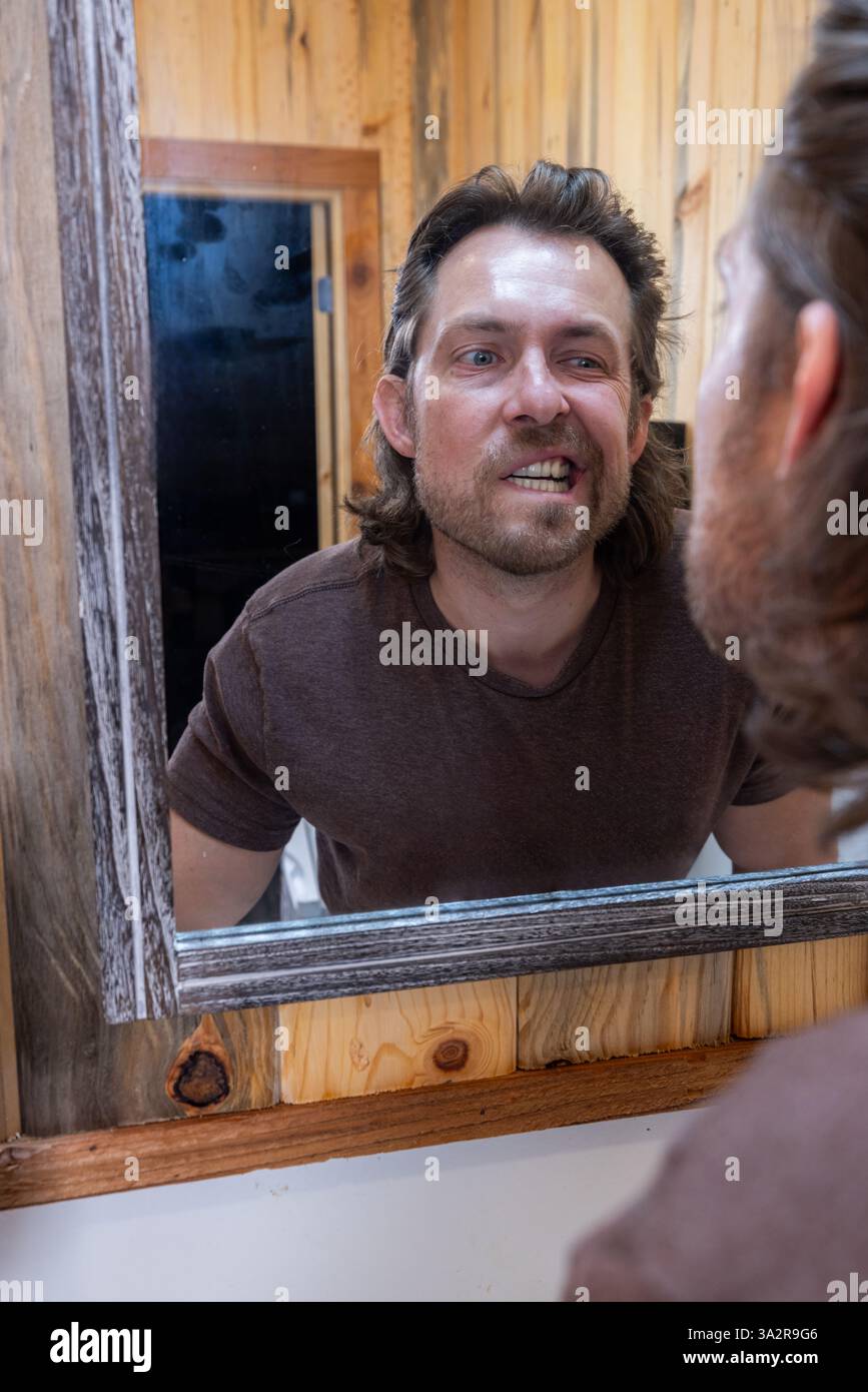 Adult male looking on a mirror to his Bell's Palsy, a temporary facial ...