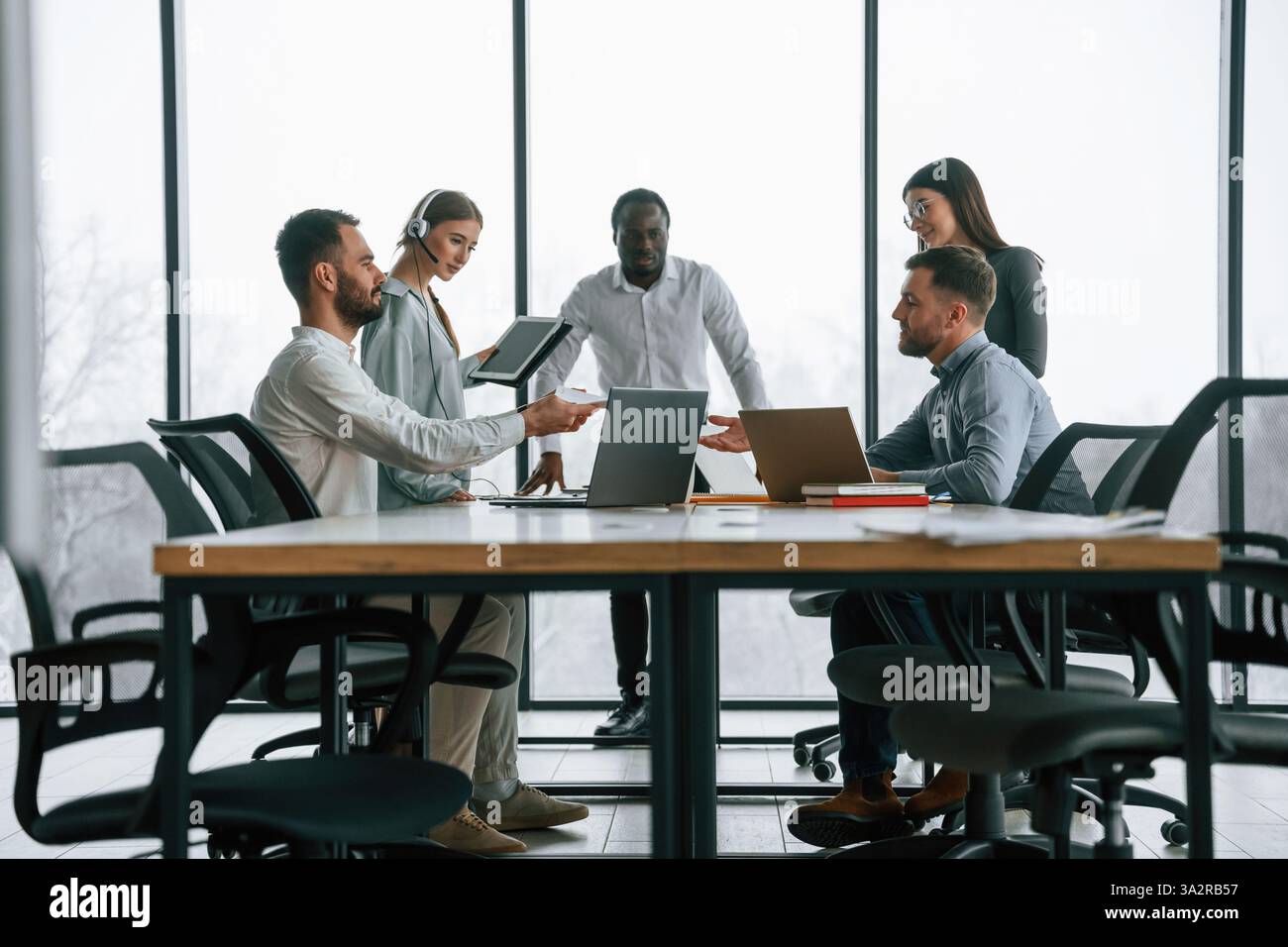 Against big panoramic windows. Team of office workers are together ...