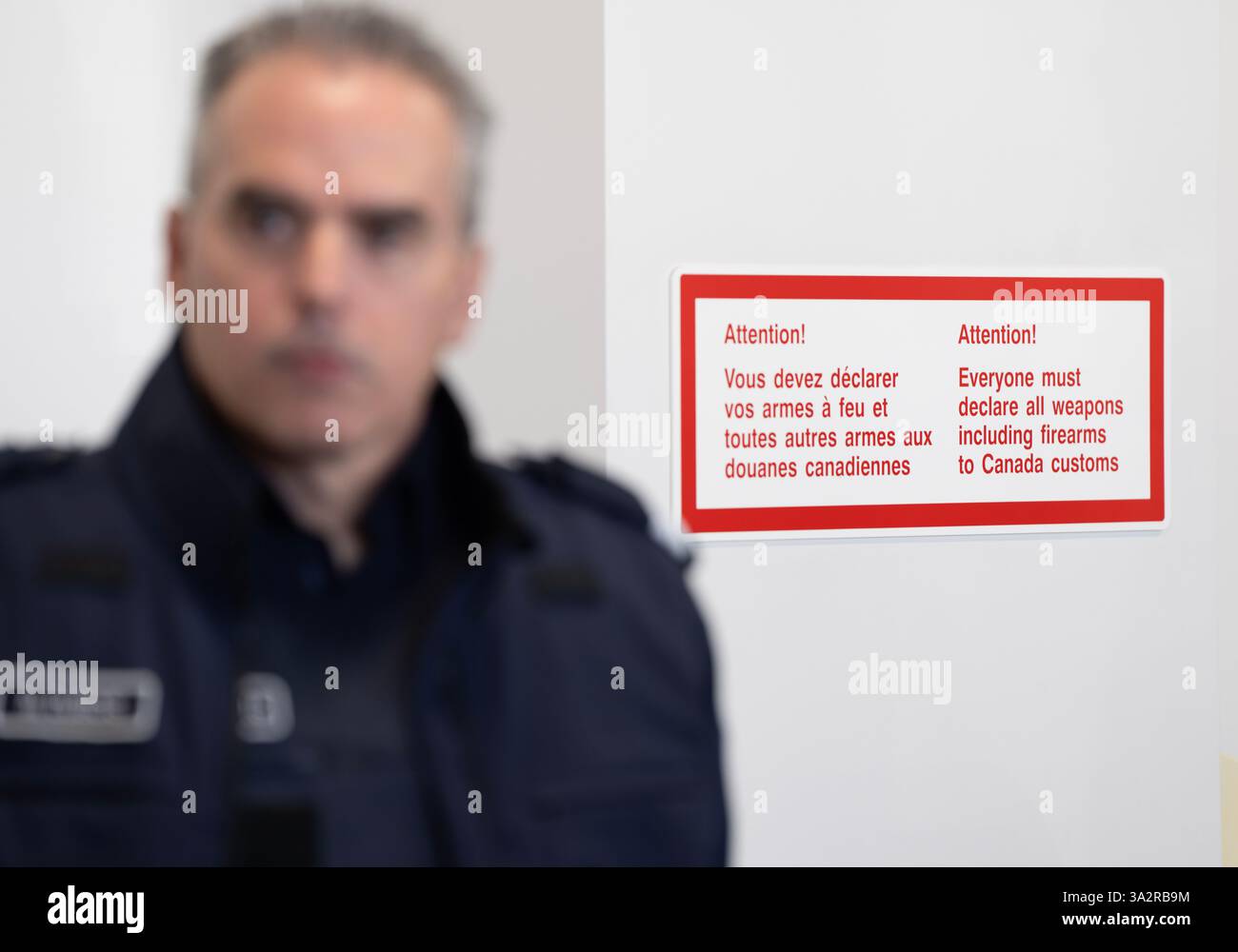 A Canada Border Services officer stands by a sign warning travellers to ...