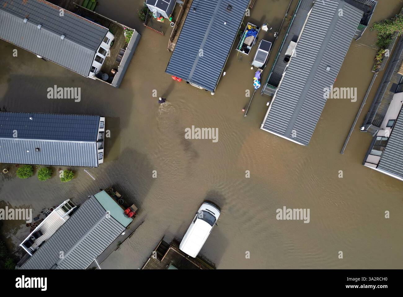 A man wades through floodwater to check on a resident at Cogenhoe Mill ...