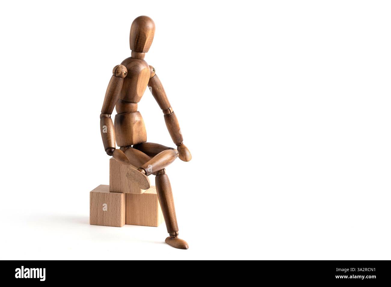 Wooden figure mannequin sitting on wooden box is highlighted on white ...