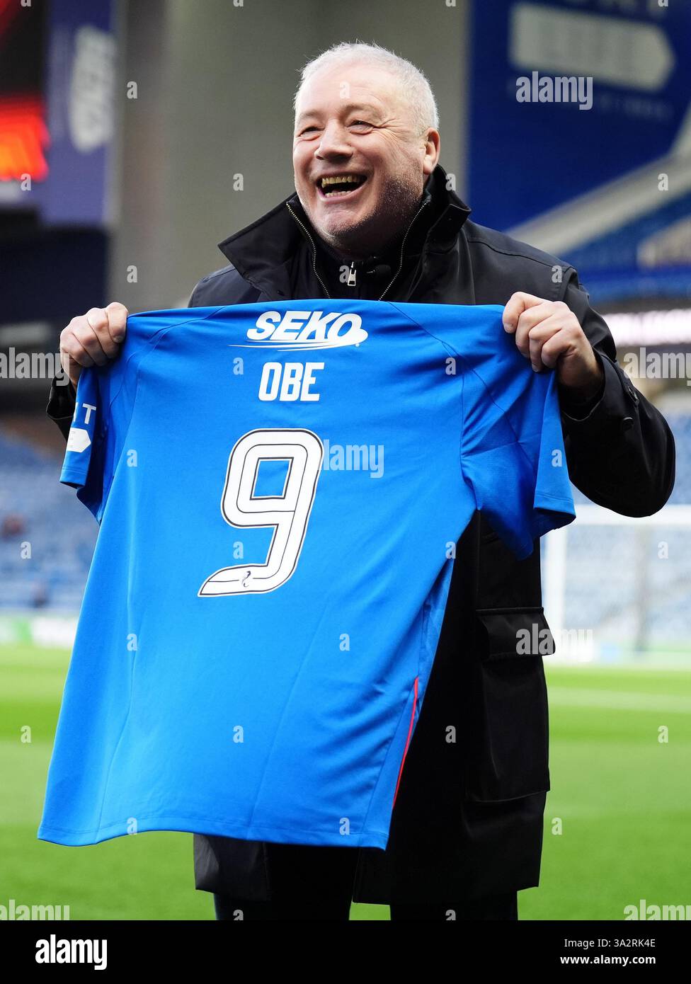 Former Rangers player Ally McCoist holding a shirt with the letters OBE ...