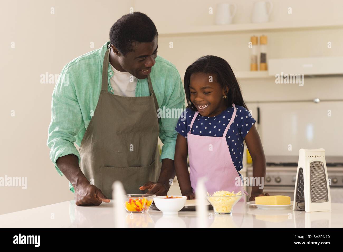 Cooking in kitchen, African American father and child sharing laughter ...