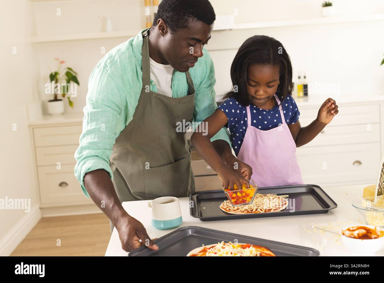 African American father and daughter making homemade pizza together in ...