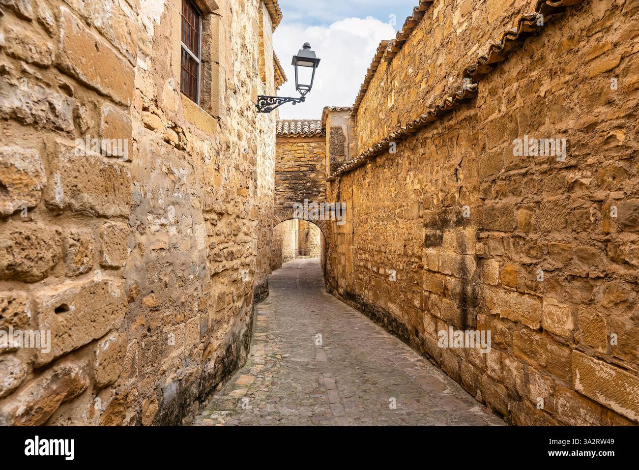 Narrow alley with very old stone walls and medieval arches in the ...
