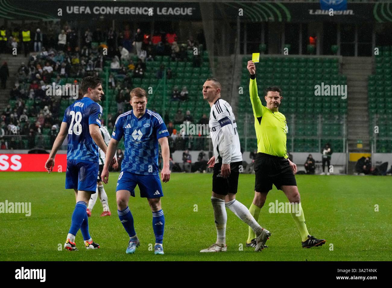 Referee Matej Jug shows the yellow card to Legia's Artur Jedrzejczyk, second from right, during ...