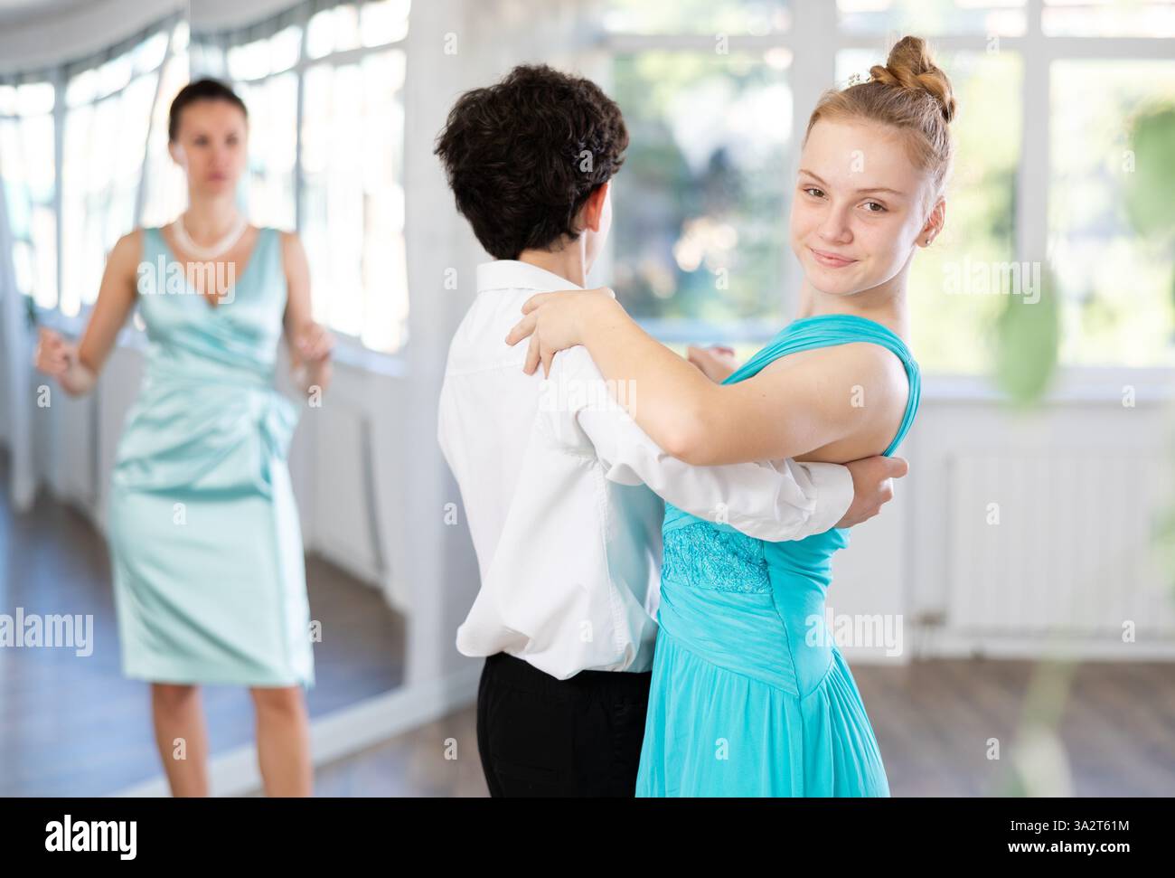 Girl and a boy in festive clothes learn to dance tango under guidance ...