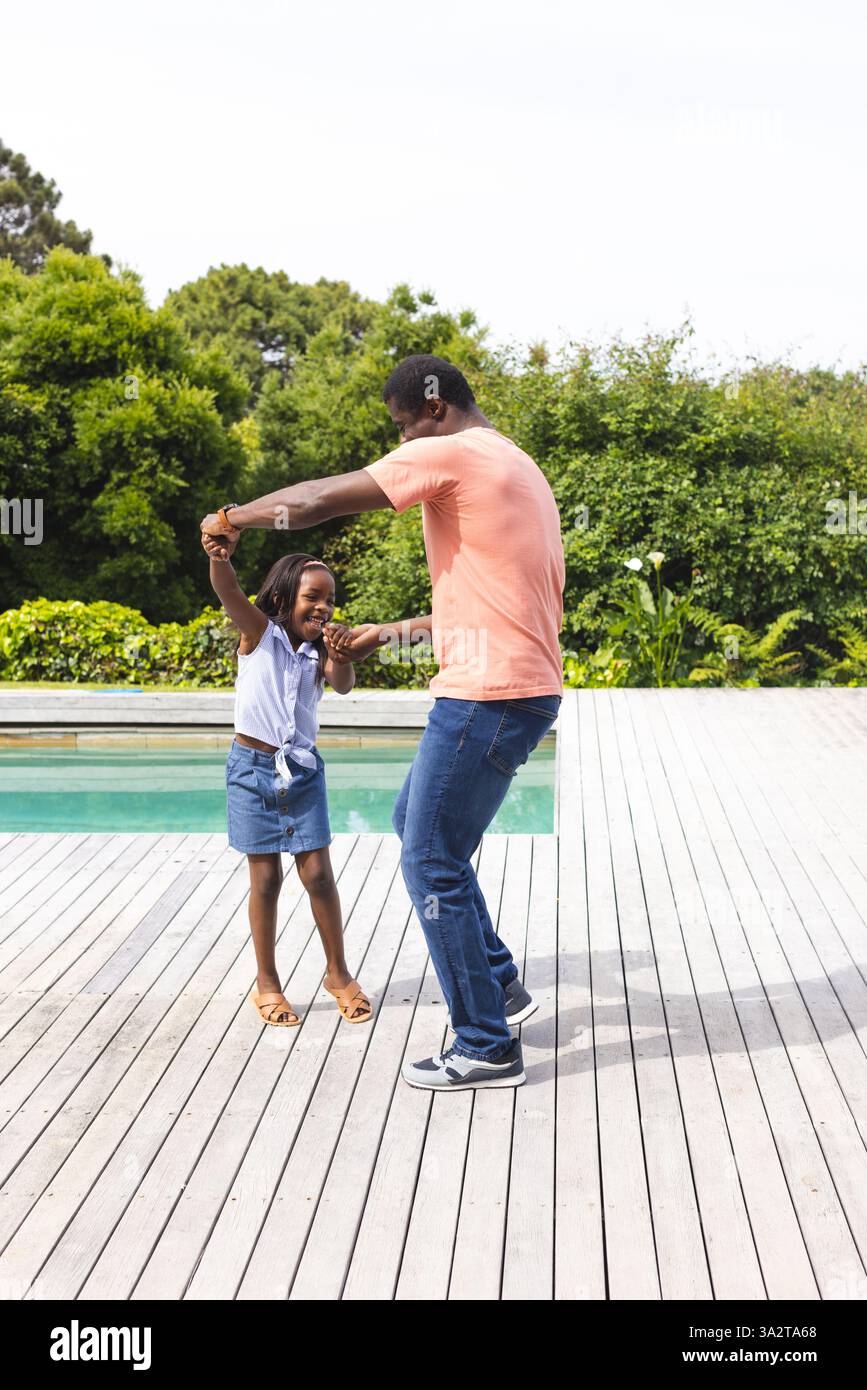 African American father and daughter dancing joyfully by poolside ...