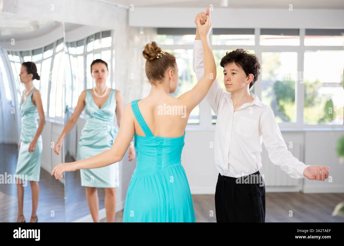 Couple of teenagers in evening dresses are learning to dance an ...