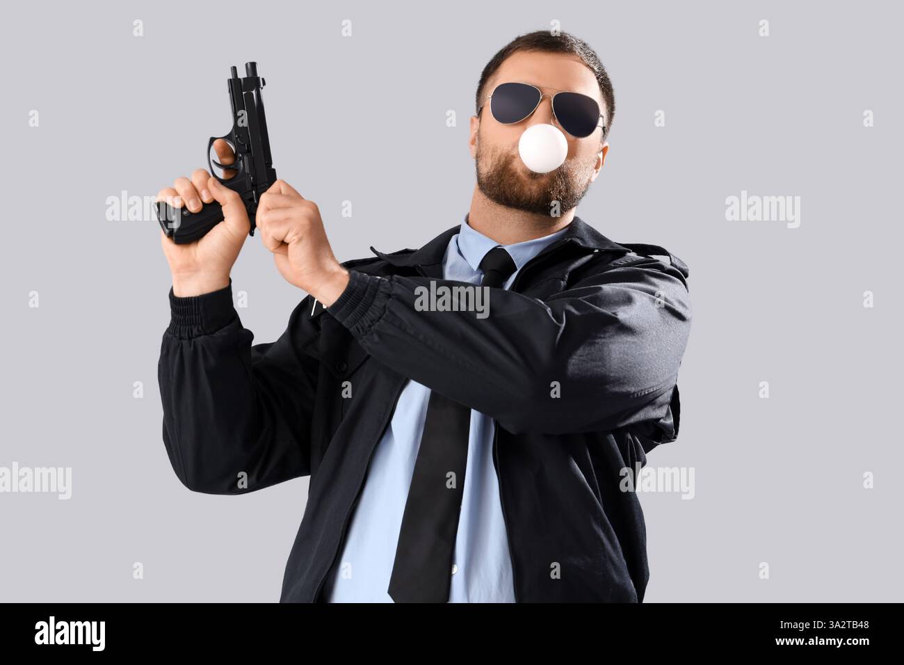 Male police officer with gun blowing bubble gum on grey background ...