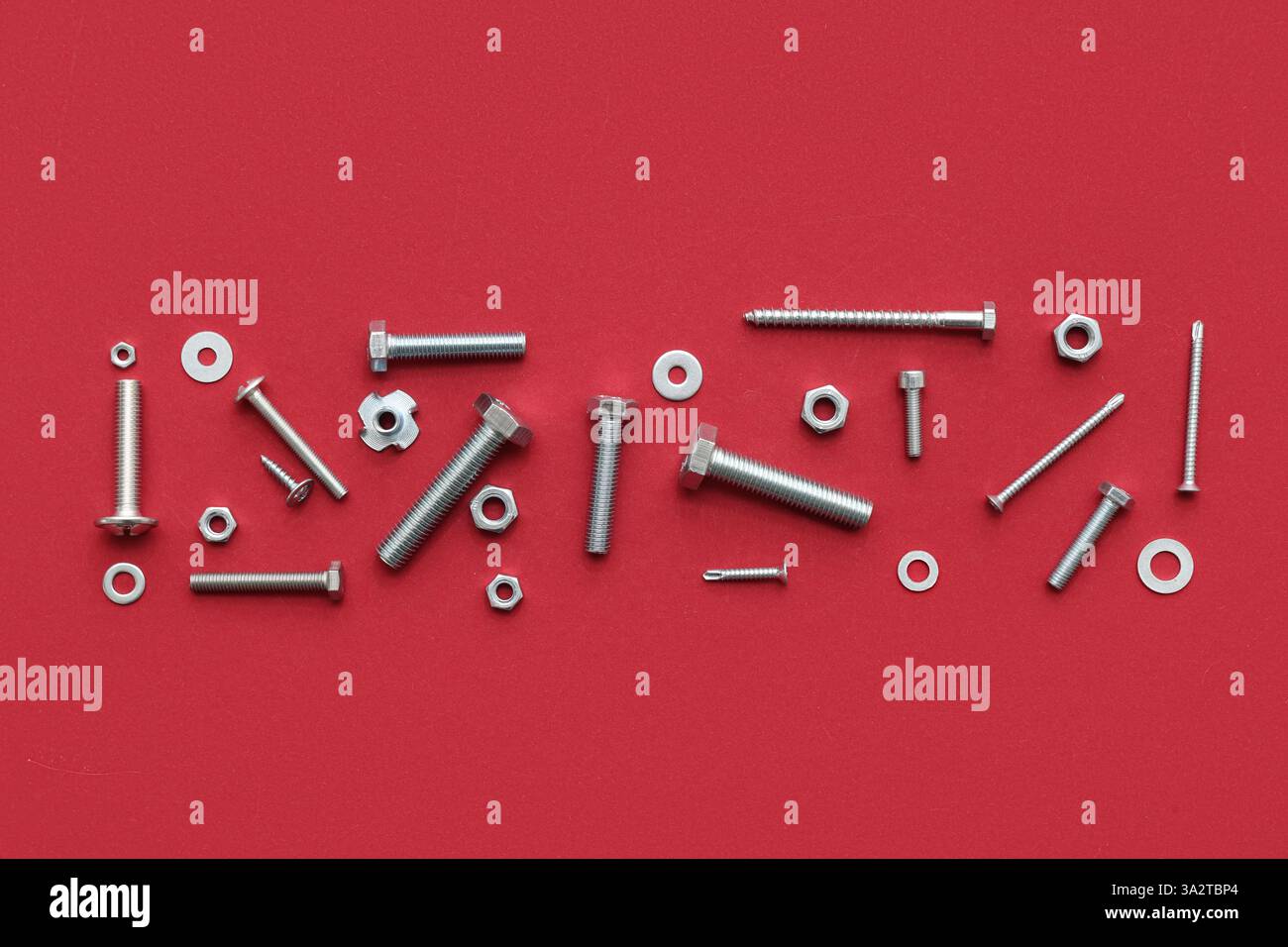 Different tap bolts, screws and chrome nuts on red background Stock ...