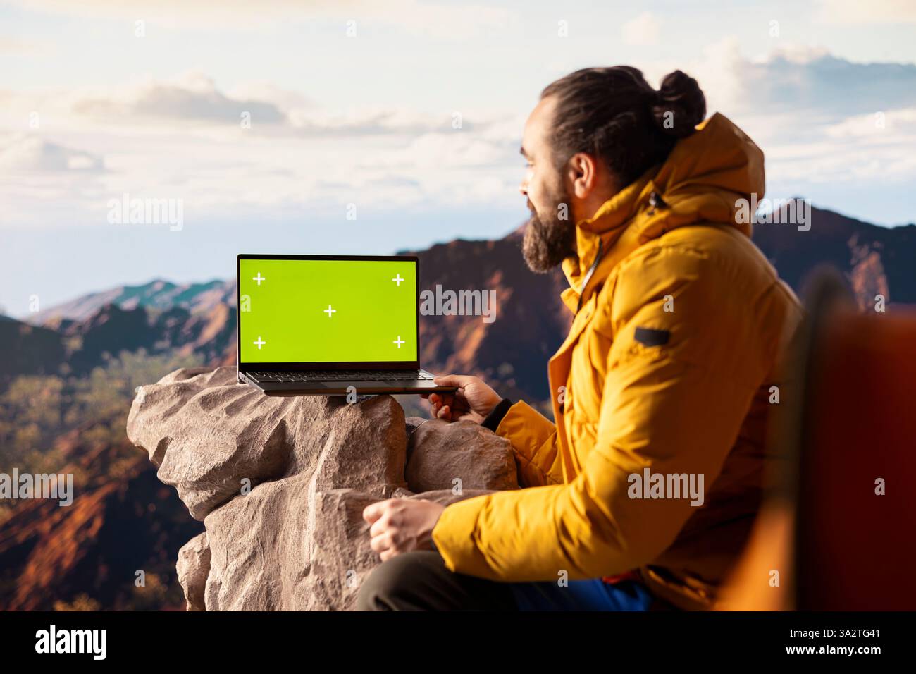 Young traveler embraces high altitude wilderness next to chroma key, using a device where the ...