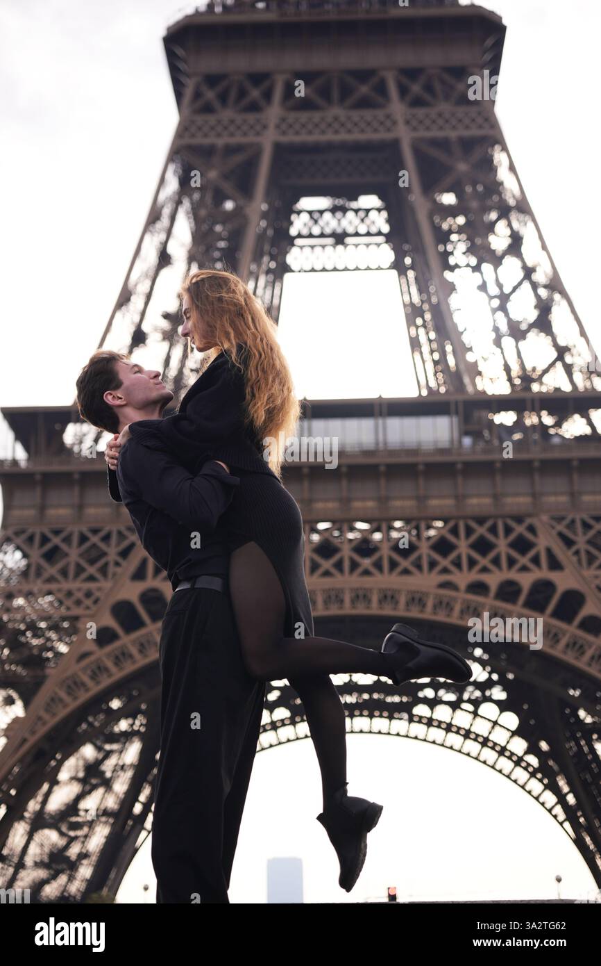 A young couple shares a romantic moment beneath the Eiffel Tower in ...