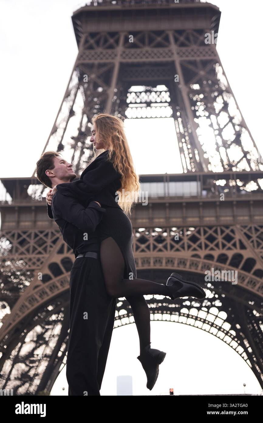 A romantic couple shares an intimate moment in Paris. The man lifts the ...